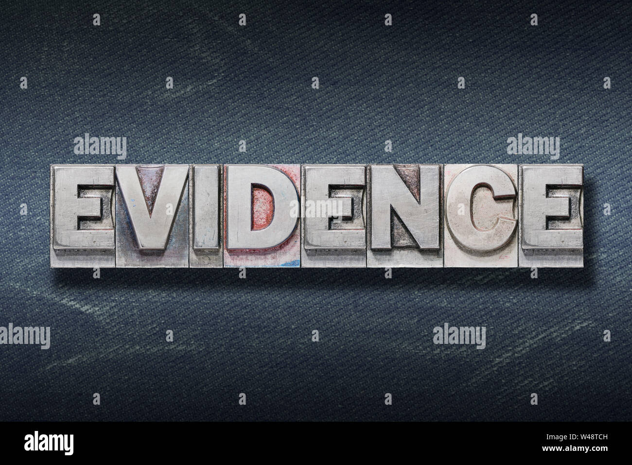 evidence word made from metallic letterpress on dark jeans background ...