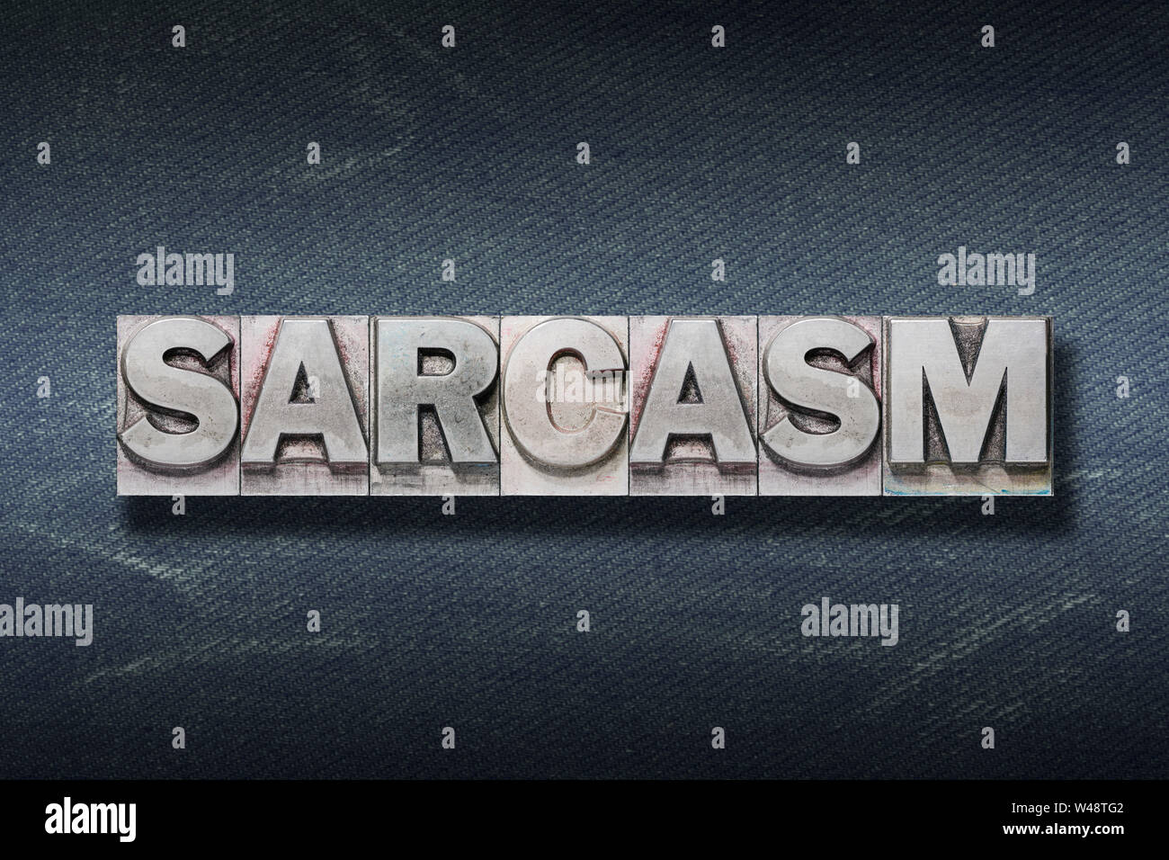 sarcasm word made from metallic letterpress on dark jeans background ...