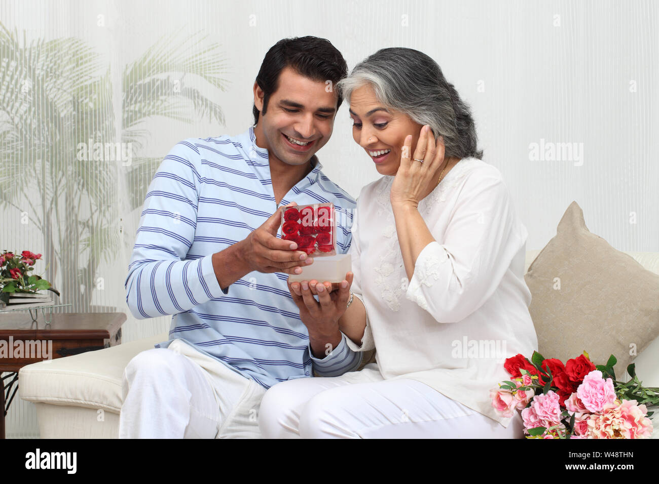 Man showing gift to his mother looking surprised Stock Photo - Alamy