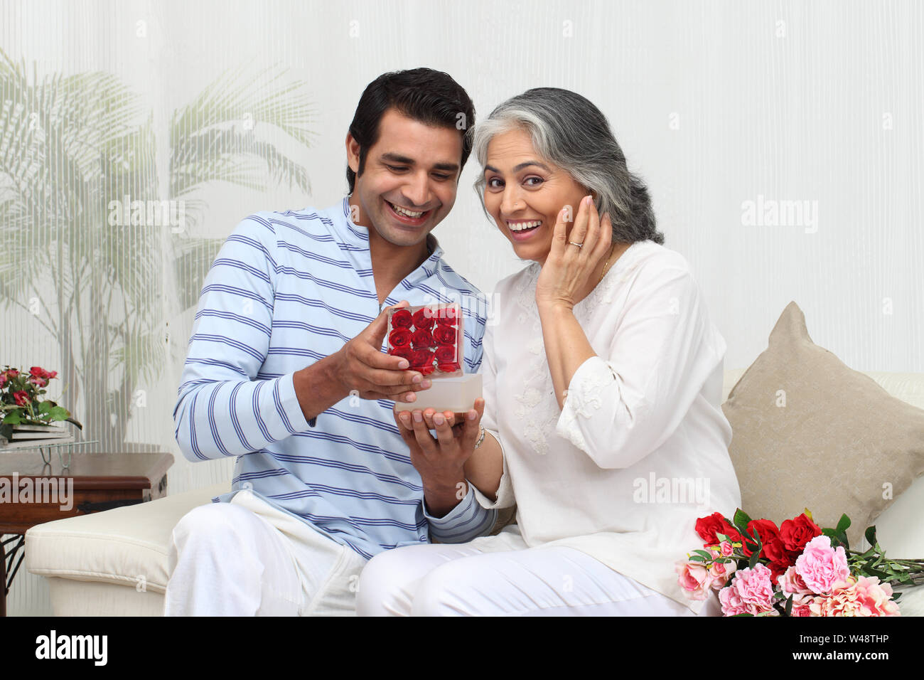 Man showing gift to his mother looking surprised Stock Photo - Alamy