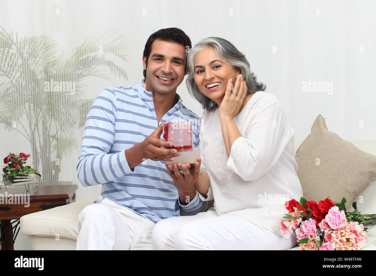 Man showing gift to his mother and smiling Stock Photo - Alamy