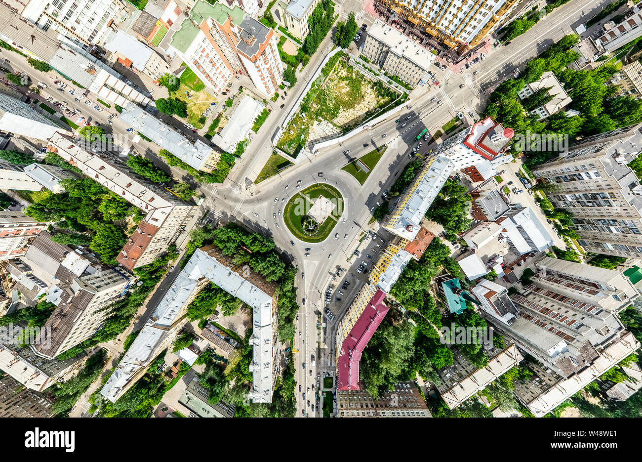 Aerial city view with crossroads and roads, houses, buildings, parks and parking lots. Sunny ...