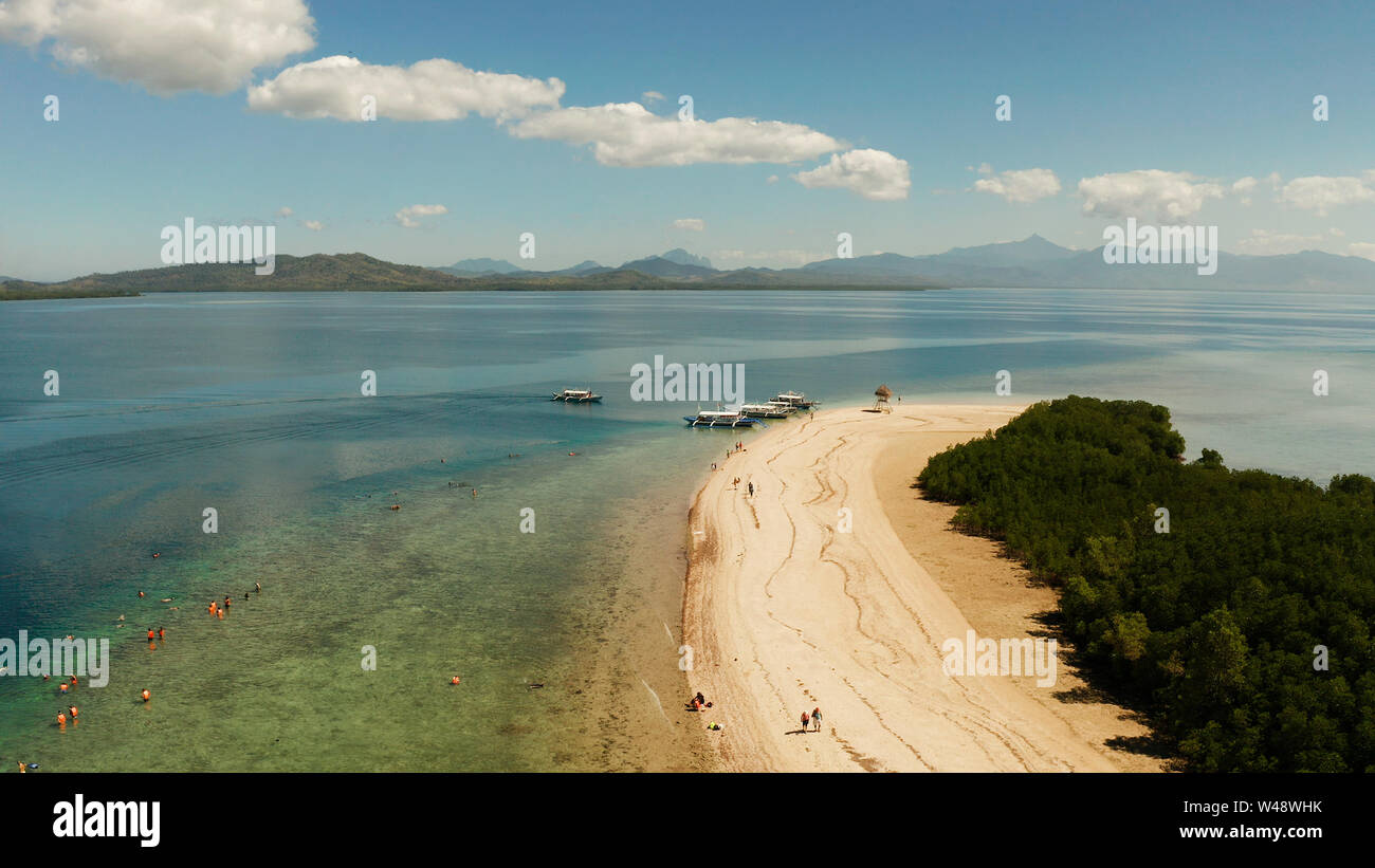 Tropical island and sandy beach with tourists surrounded by coral reef ...