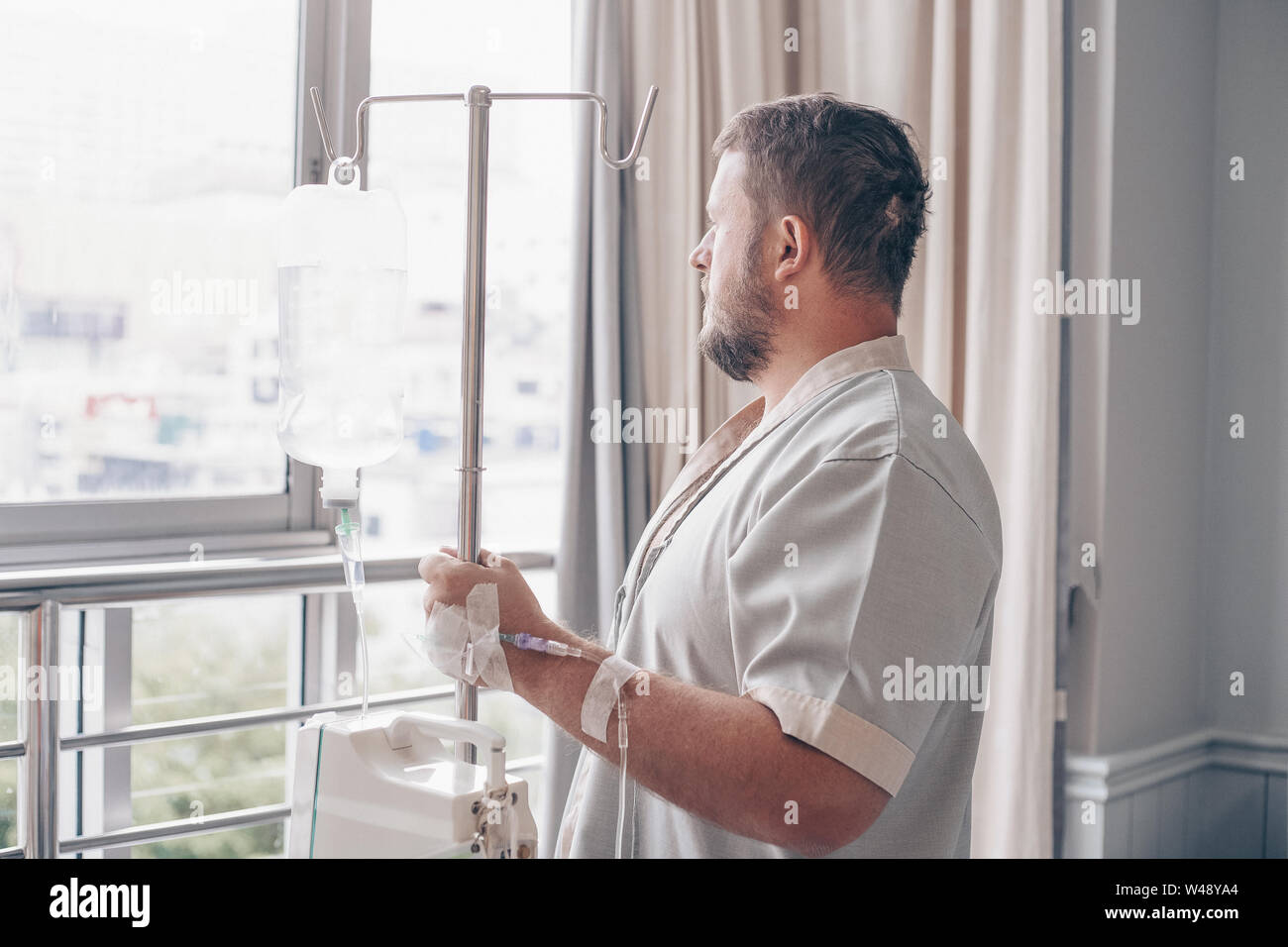 A man stands in a hospital ward and looks out the window. Dropper in a ...