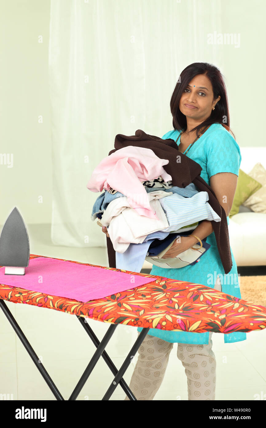 Woman carrying clothes for ironing Stock Photo - Alamy
