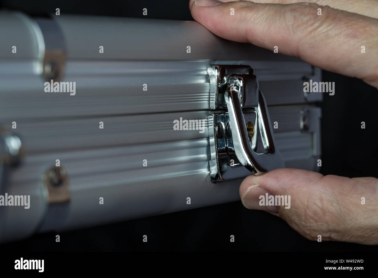 Macro of human hand opening or closing metal briefcase Stock Photo - Alamy