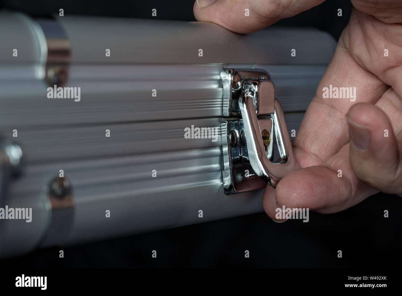 Macro of human hand opening or closing metal briefcase Stock Photo - Alamy