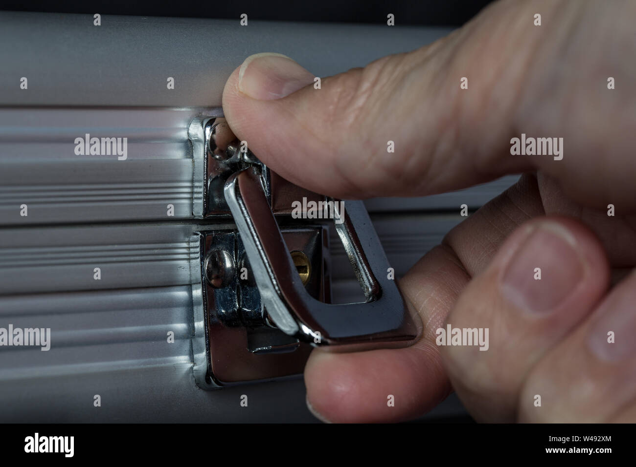 Macro of human hand opening or closing metal briefcase Stock Photo - Alamy