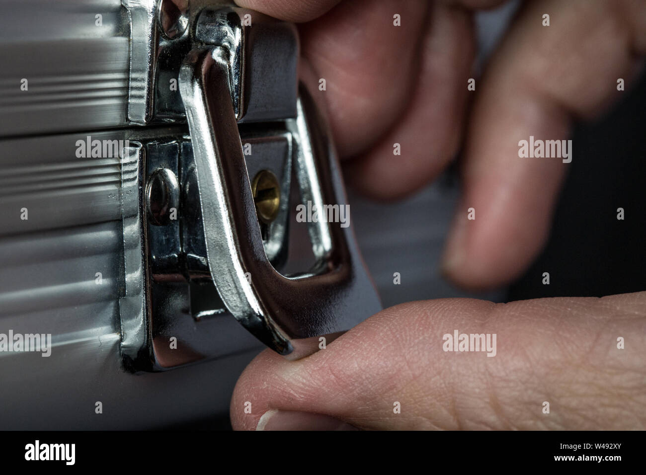 Macro of human hand opening or closing metal briefcase Stock Photo - Alamy