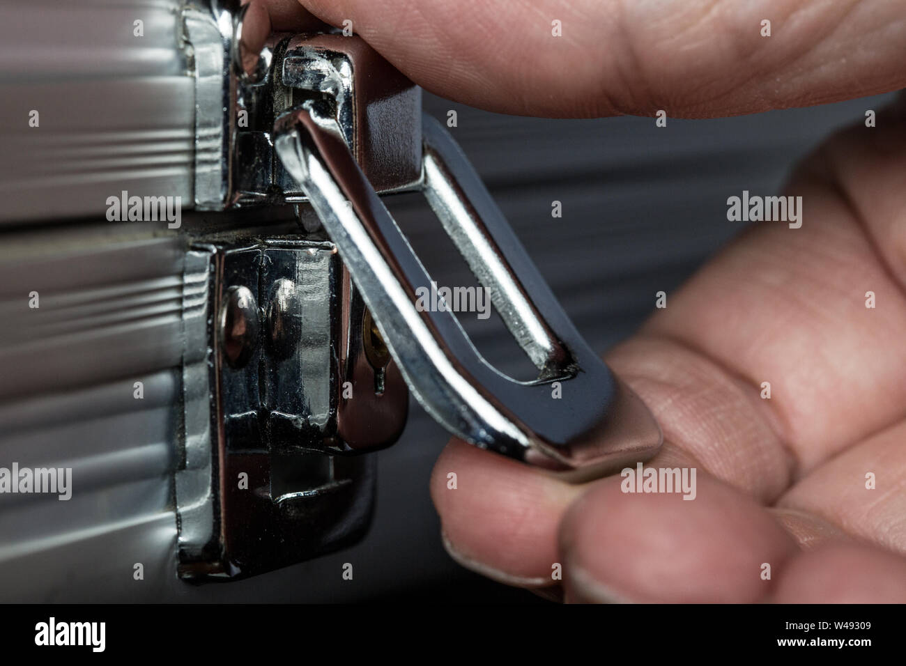 Macro of human hand opening or closing metal briefcase Stock Photo - Alamy