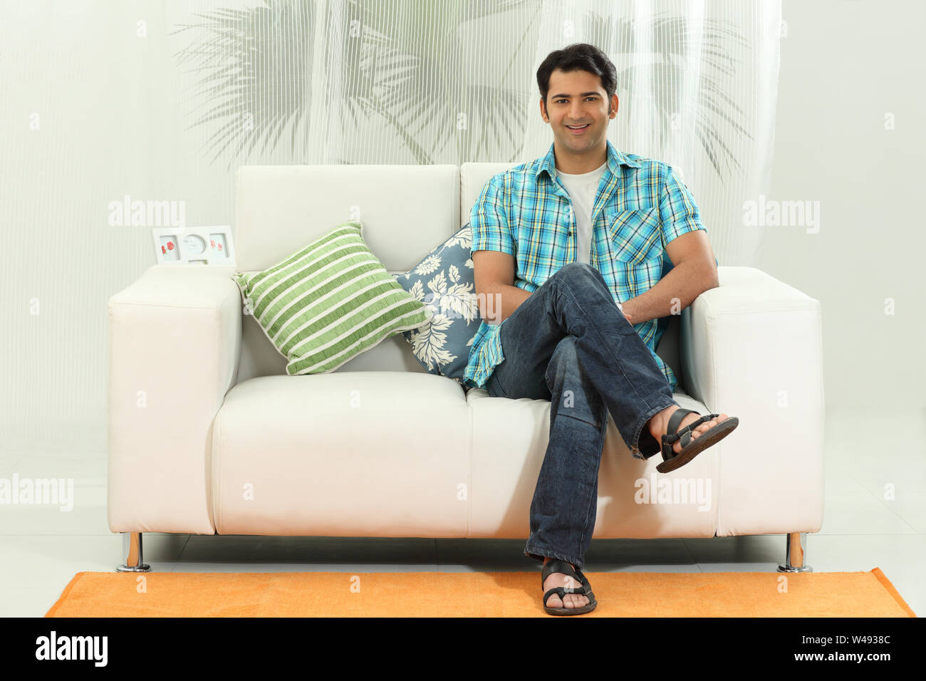 Man sitting on a couch at home Stock Photo - Alamy