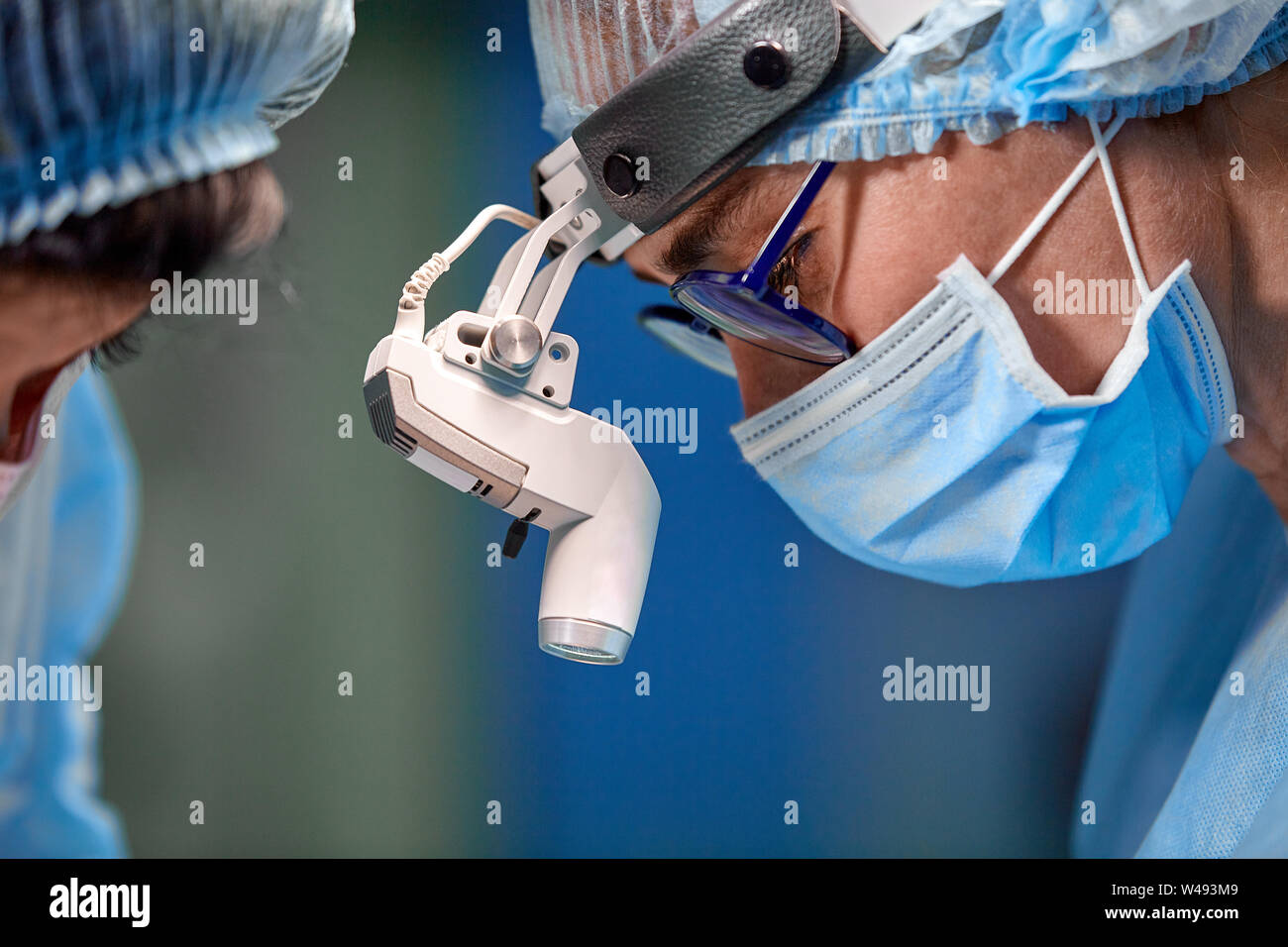 Surgeon and his assistant performing cosmetic surgery on nose in ...