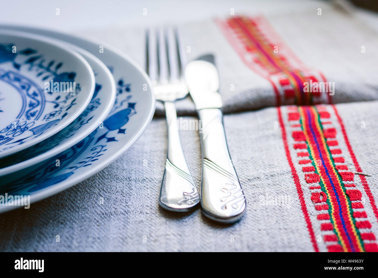 Table setting for dinner: white and blue plates, a fork, a knife on a ...
