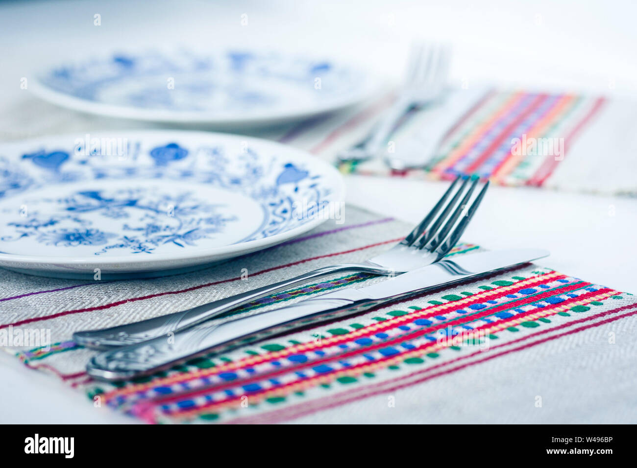 Table setting for dinner: white and blue plates, a fork, a knife on a ...