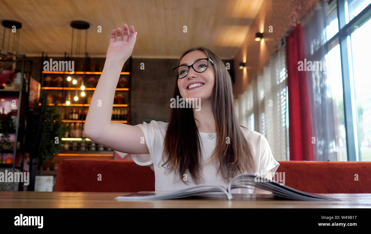 Pretty girl in glasses reading the menu and making an order Stock Photo ...