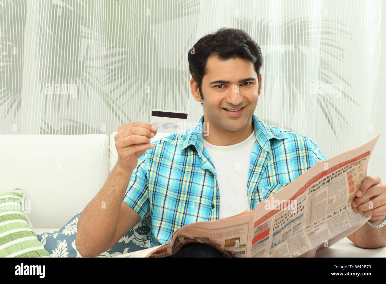 Man showing credit card and reading newspaper Stock Photo - Alamy