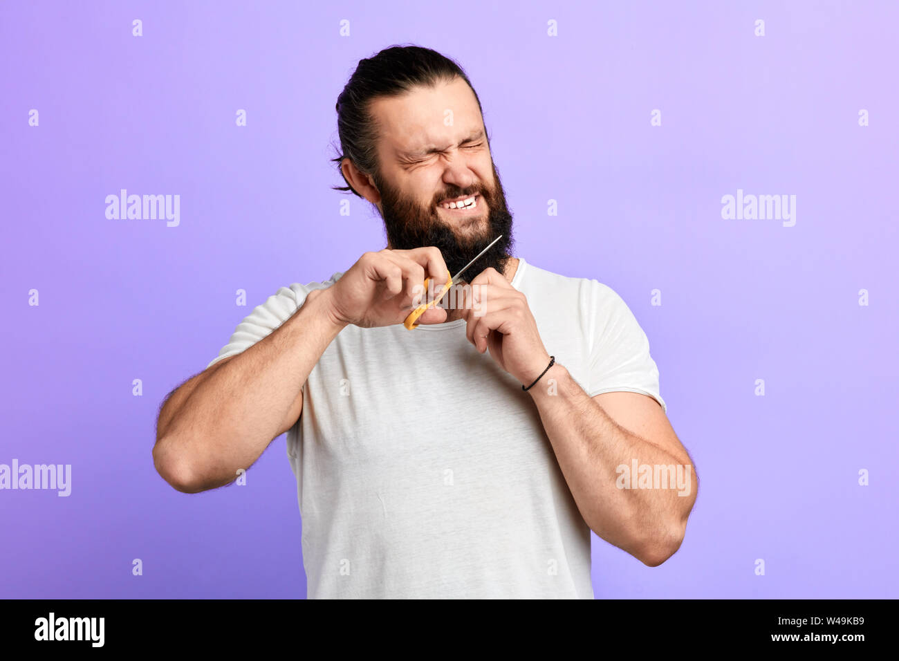 angry crazy funny man hates his beard. isolated blue background. studio ...