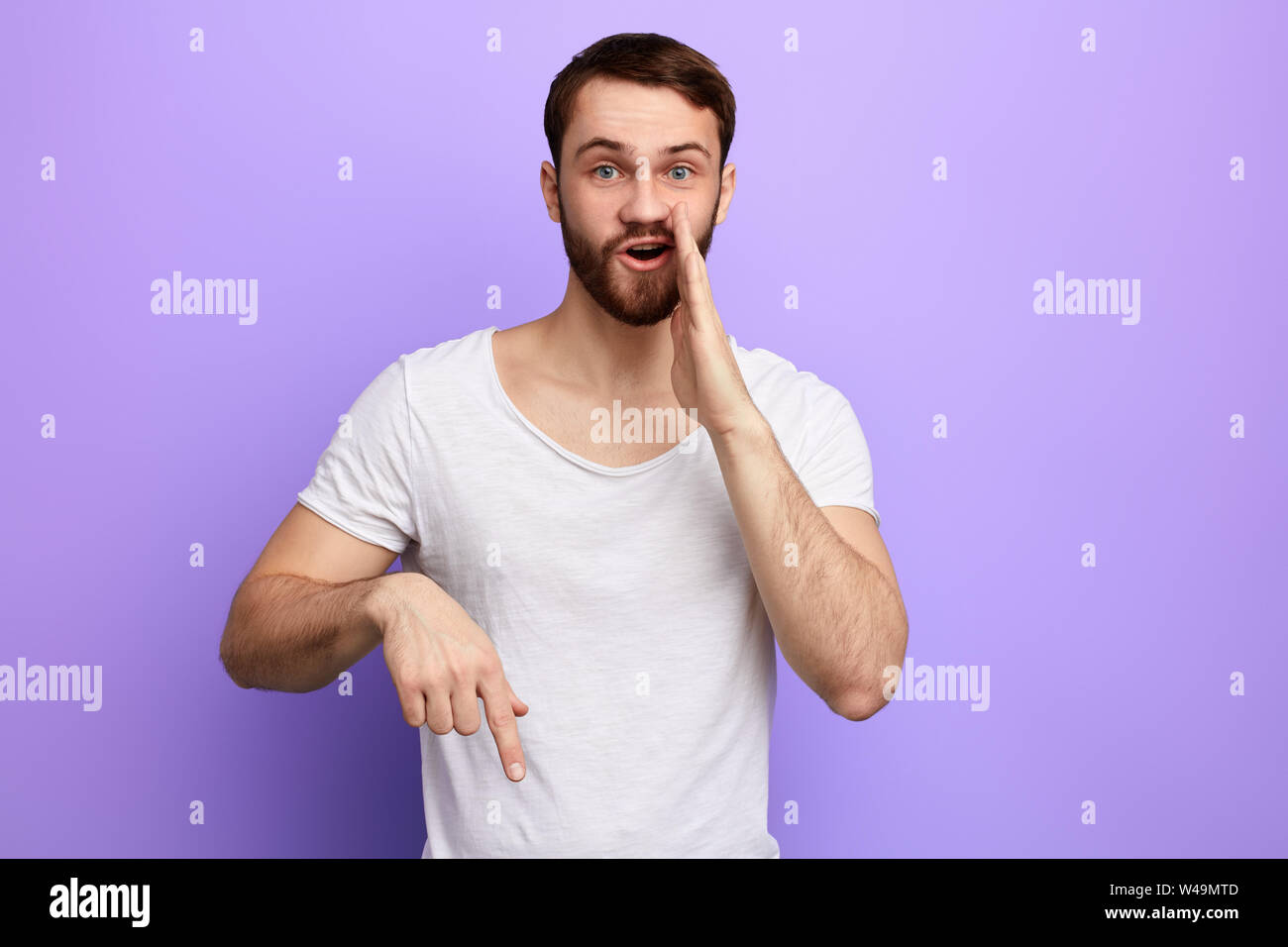 young emotional man in casual clothes whispering secret ,pointing index ...