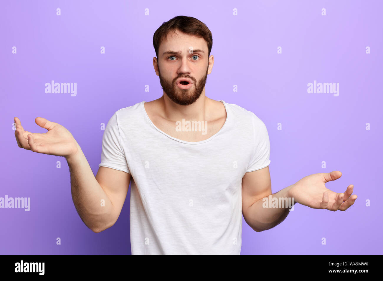 surprised handsome man shrugging his shoulder while posing to the ...