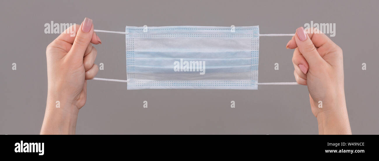 Hand holding medical protective mask on grey background Stock Photo - Alamy