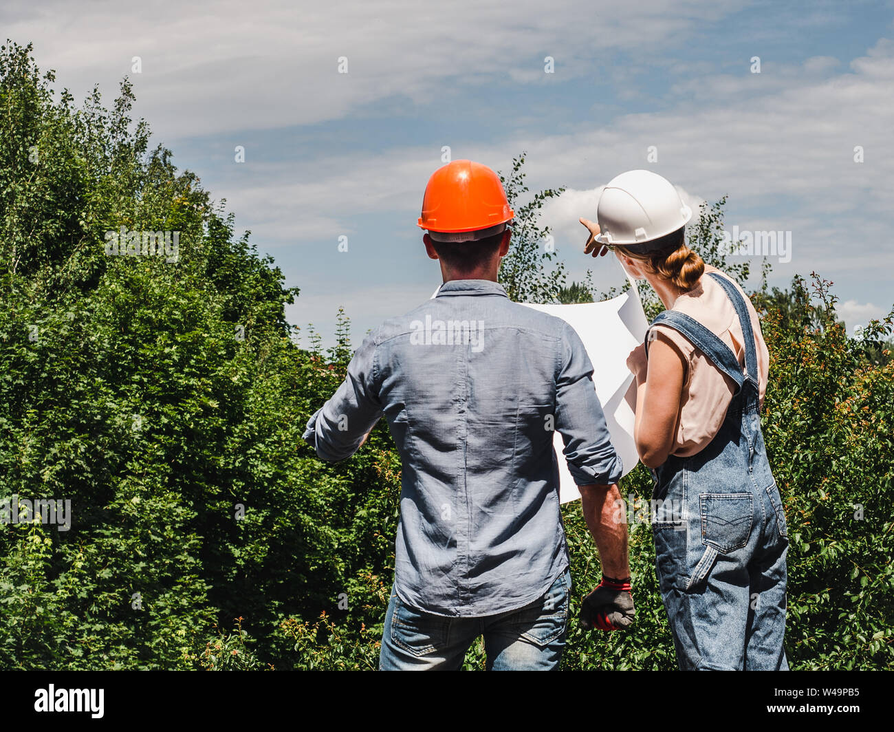 Young engineer woman and her subordinate worker holding a paper project ...