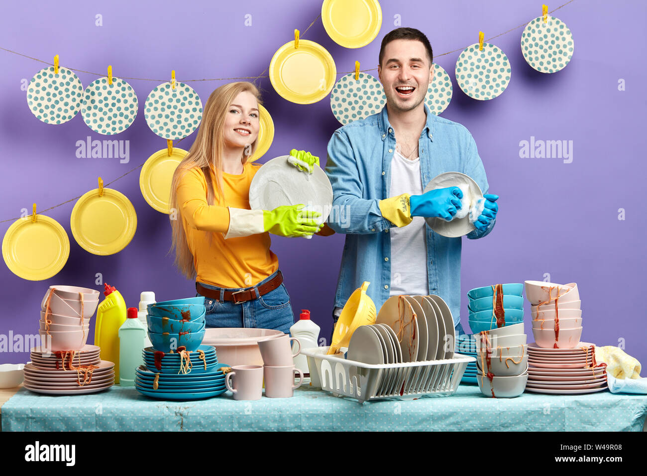 cheerful pleasant man and woman washing the plates after party. close ...
