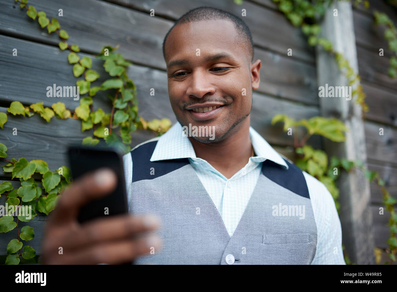 Handsome black man hanging out and texting with his mobile smartphone ...
