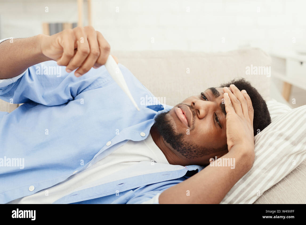 African-american man checking his body temperature at home Stock Photo ...