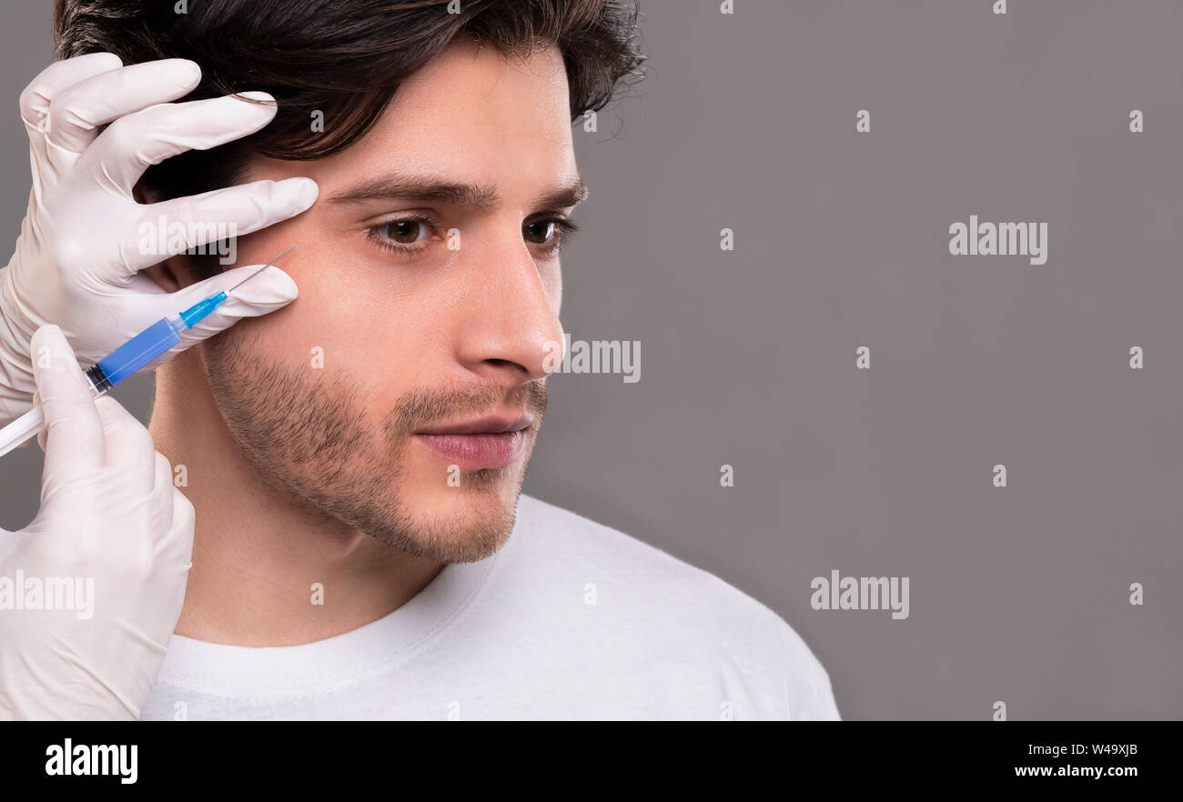 Millennial man getting hyaluronic collagen injection near eyes Stock ...