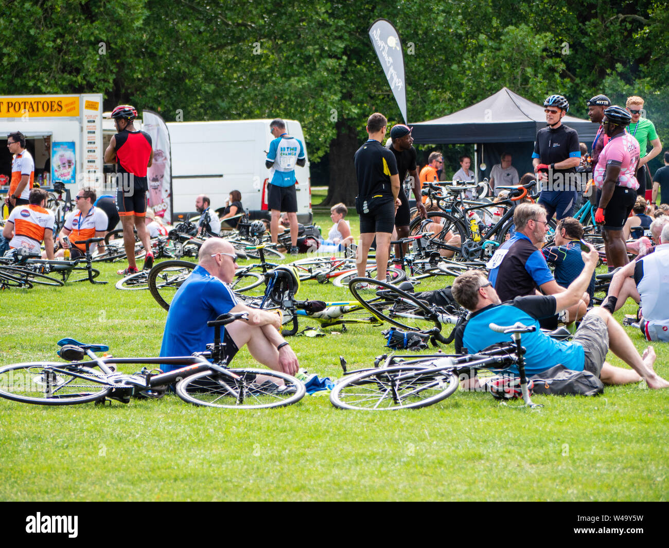 Cambridge, UK. 21, July, 2019. Cyclists rest on the grass of Jesus ...