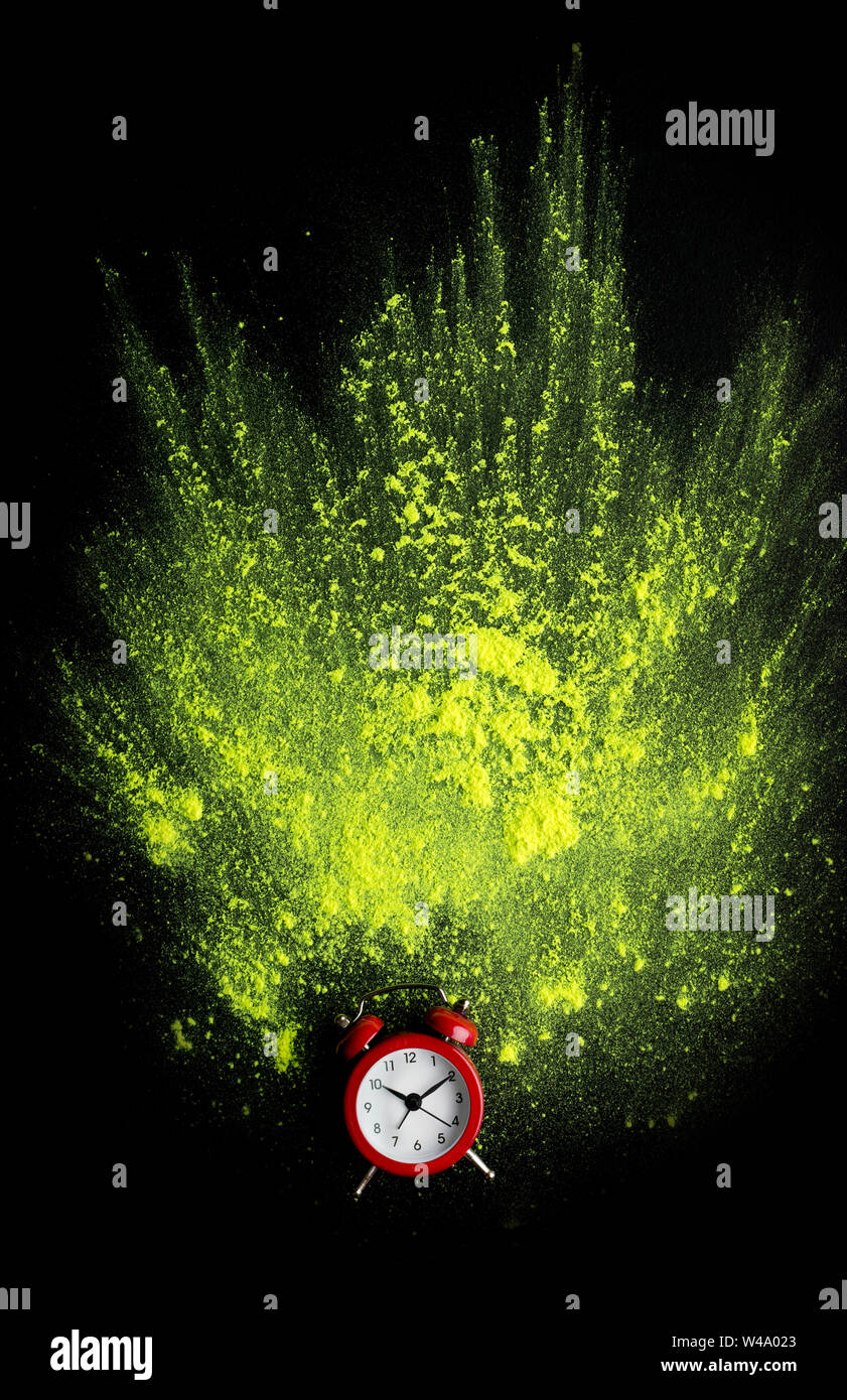 Red alarm clock with yellow holi powder explosion on black Stock Photo ...