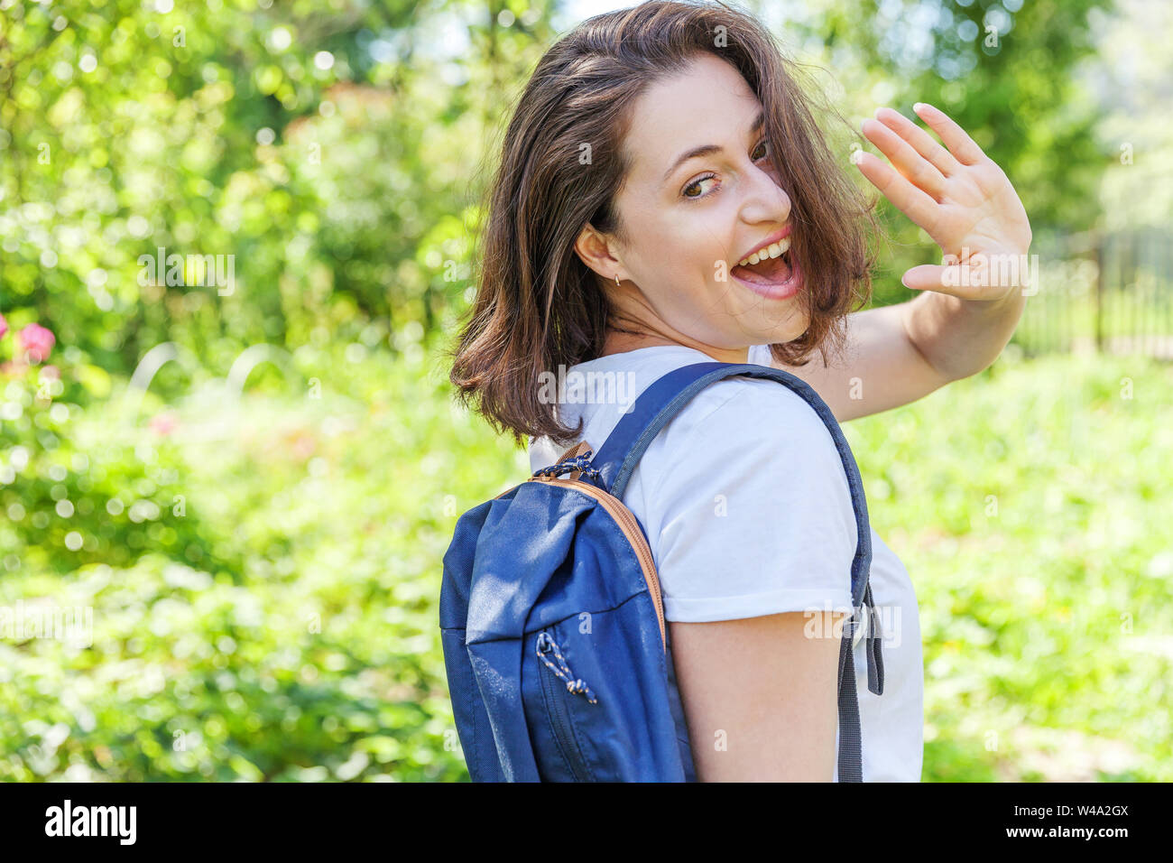 Happy positive student girl with backpack smiling on green park ...