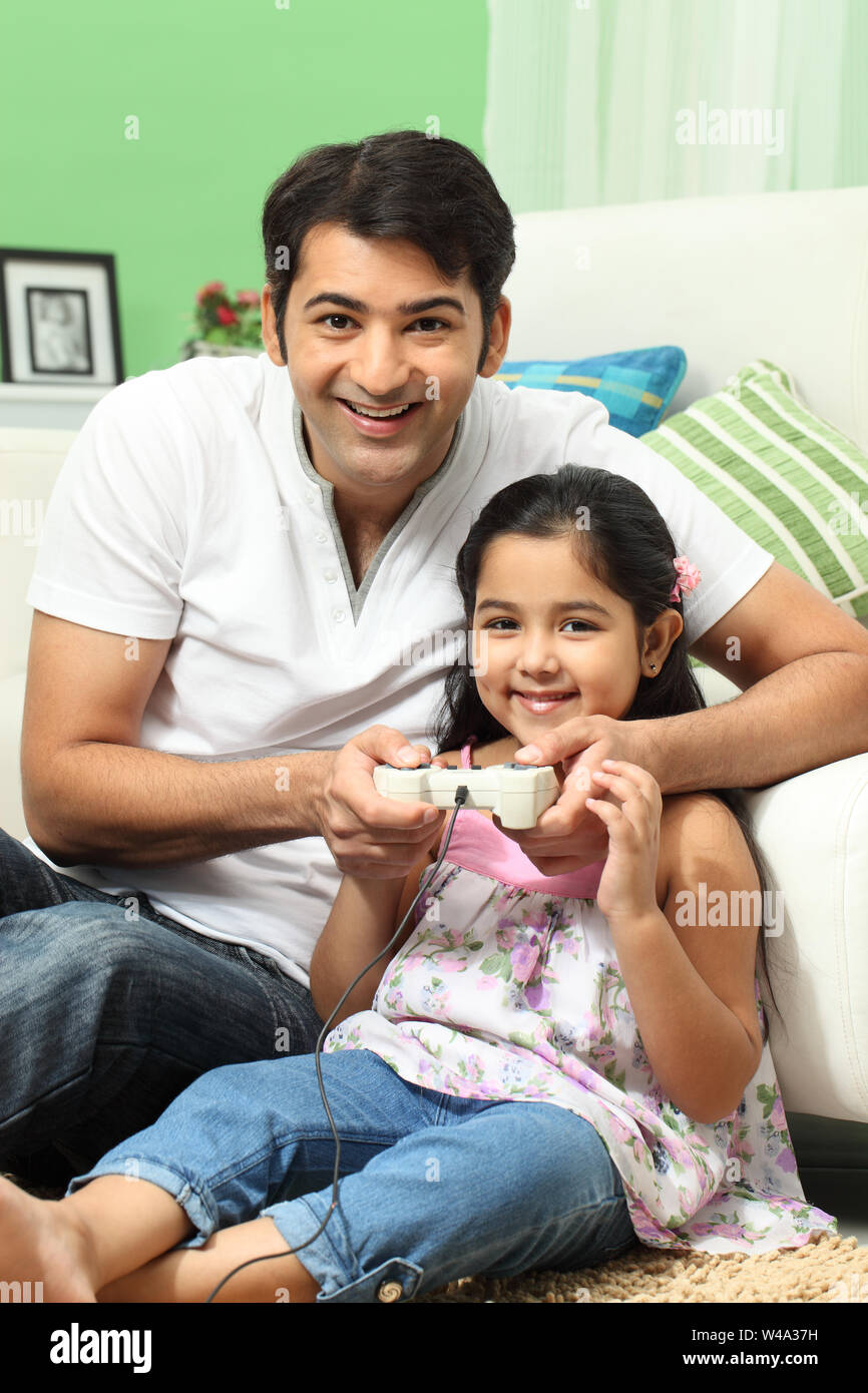 Father with daughter playing video game at home Stock Photo - Alamy