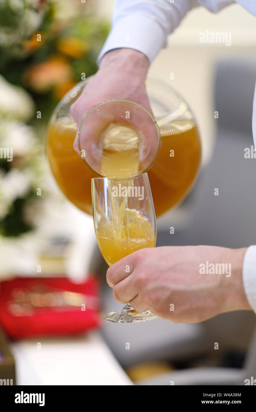The waiter pours the juice into a glass at a festive buffet table Stock ...