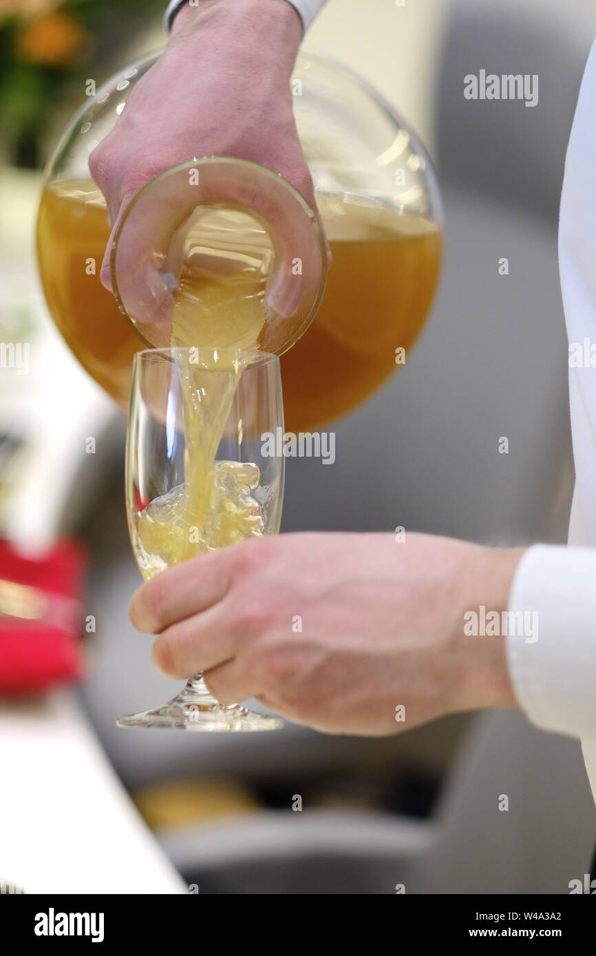 The waiter pours the juice into a glass at a festive buffet table Stock ...