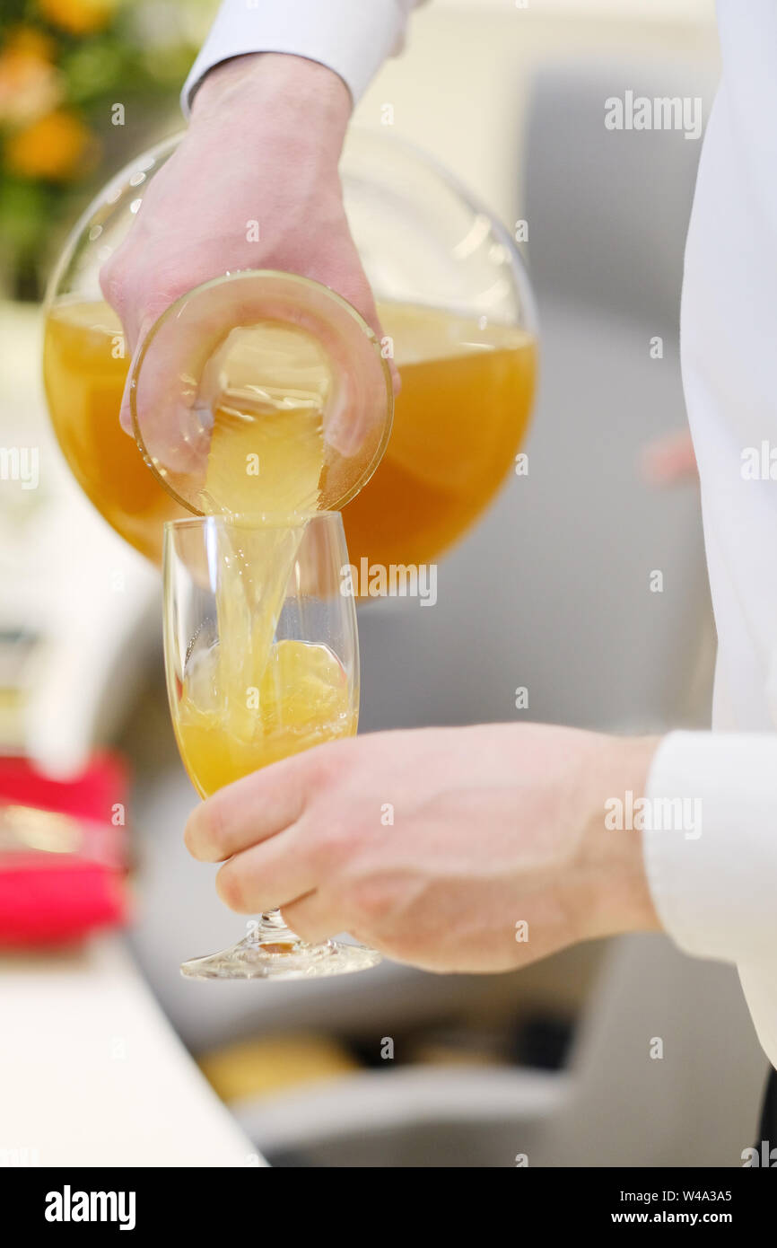 The waiter pours the juice into a glass at a festive buffet table Stock ...