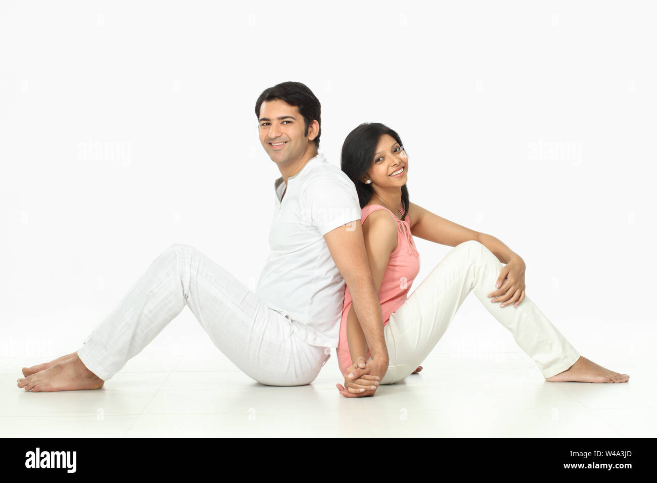 Couple sitting back to back and smiling Stock Photo - Alamy