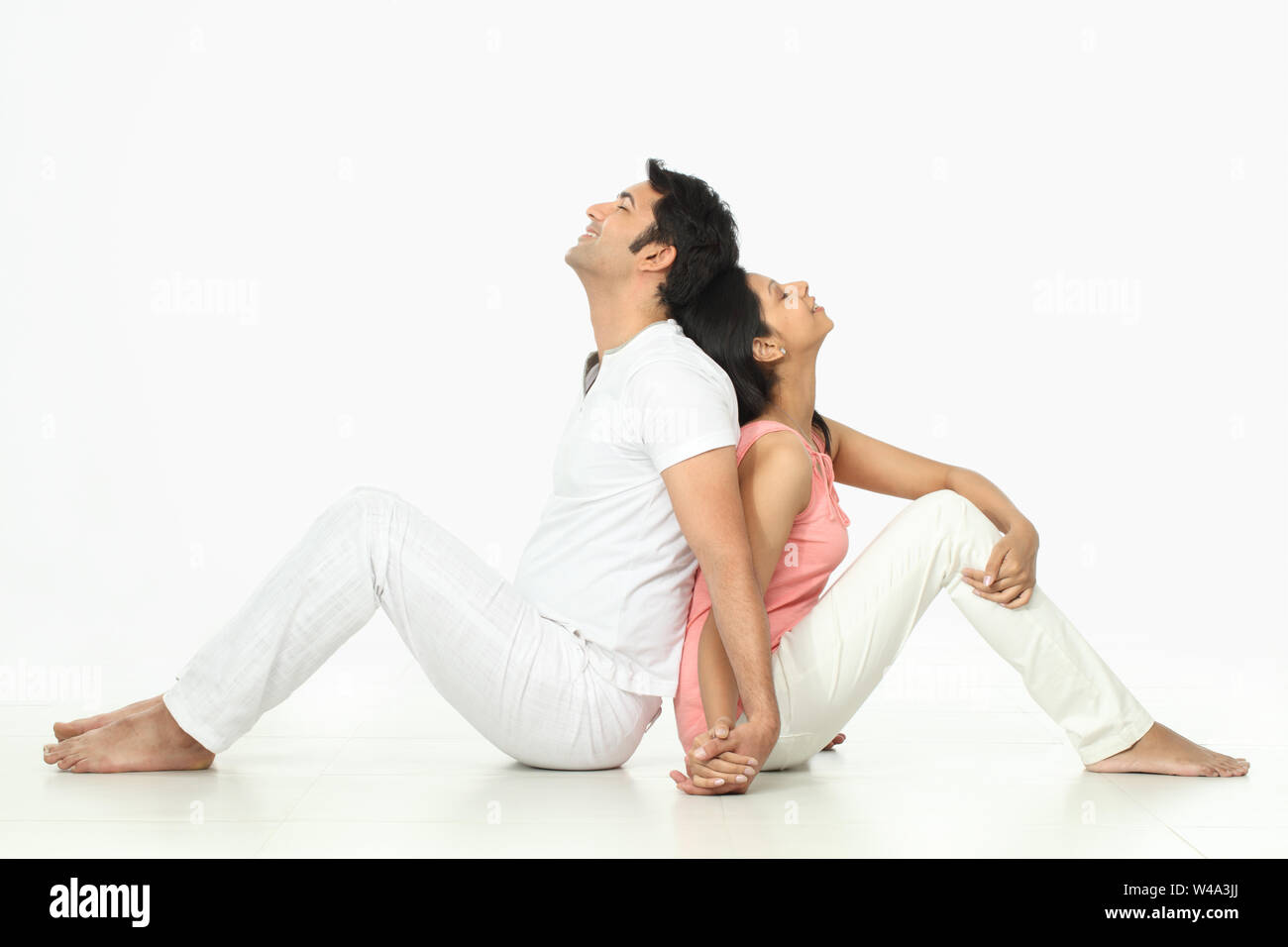 Couple sitting back to back and smiling Stock Photo - Alamy