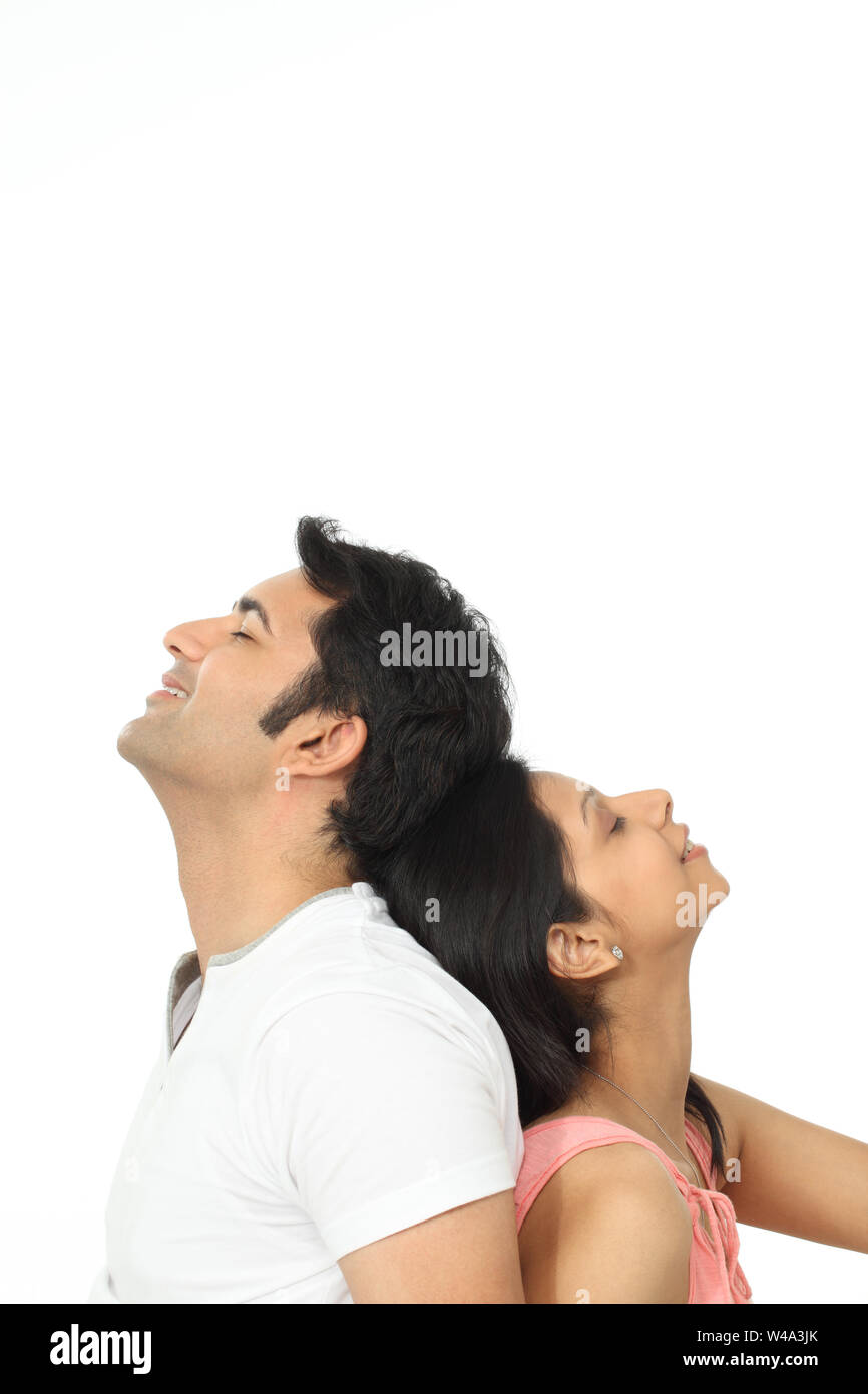 Indian young couple back to back with eyes closed Stock Photo - Alamy