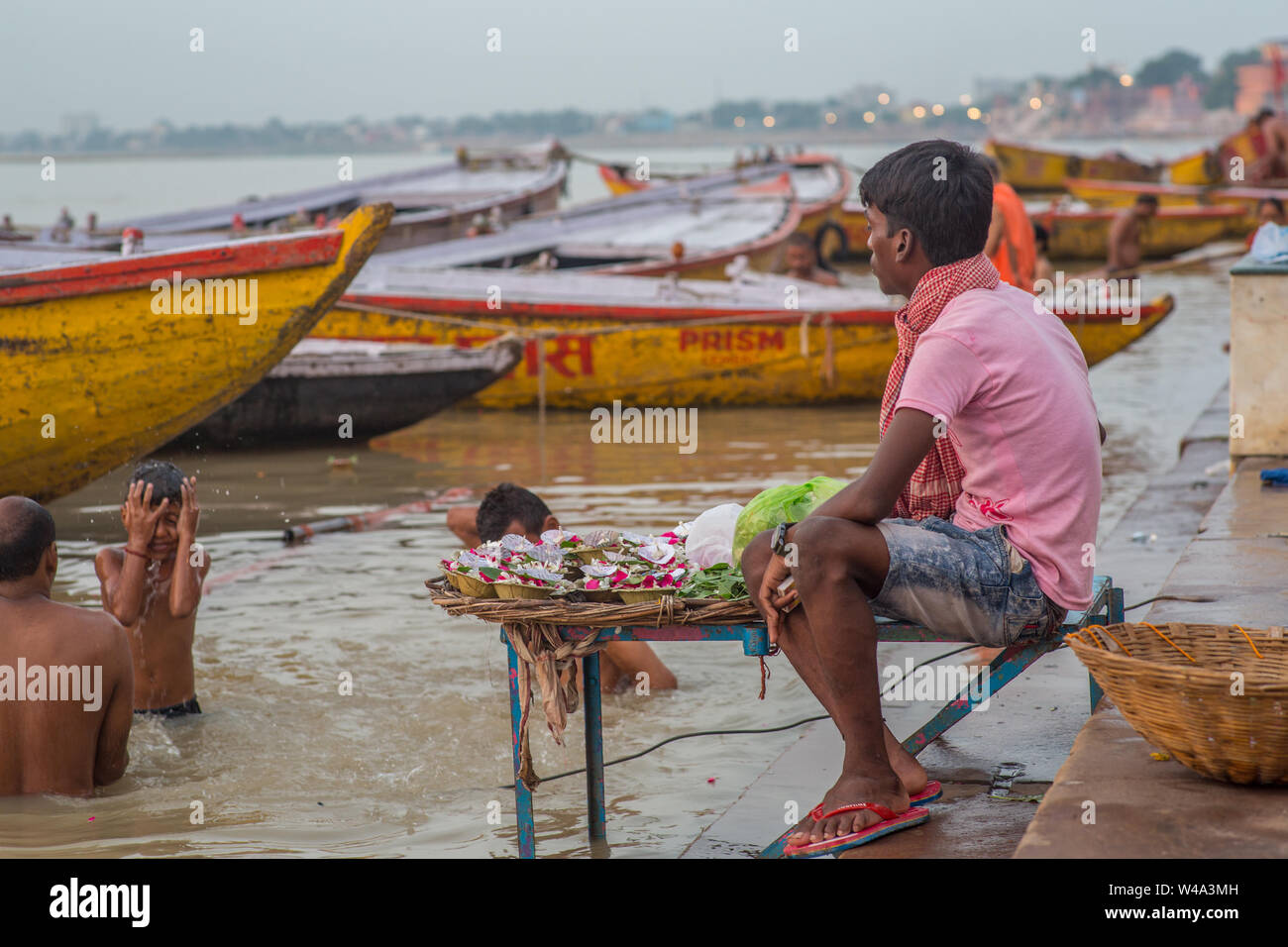 A boy selling flowers for puja offerings near the Ganges river in ...