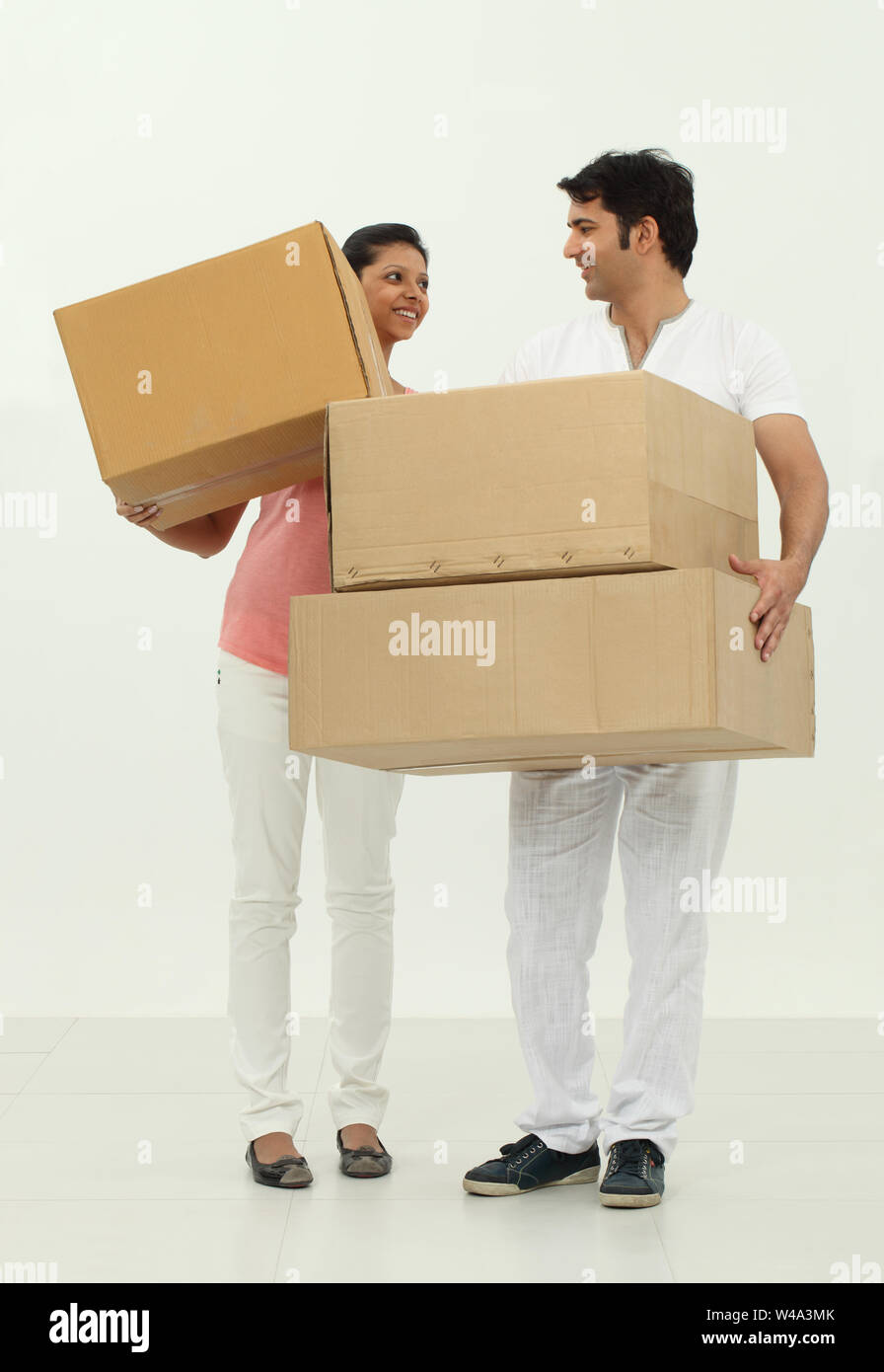Indian couple carrying moving boxes into new home Stock Photo - Alamy