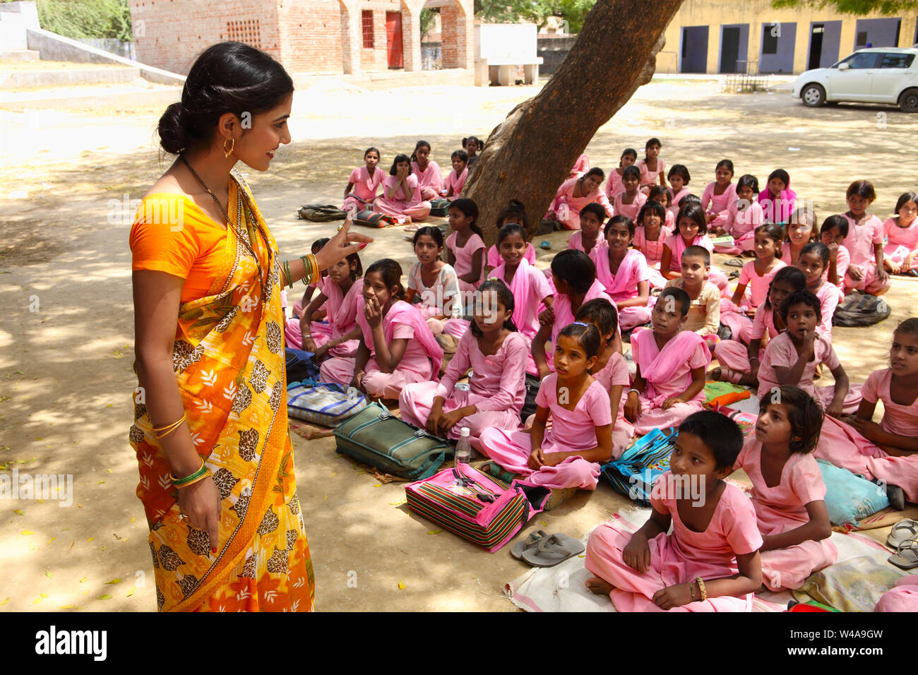 Female teacher teaching students in a class Stock Photo - Alamy
