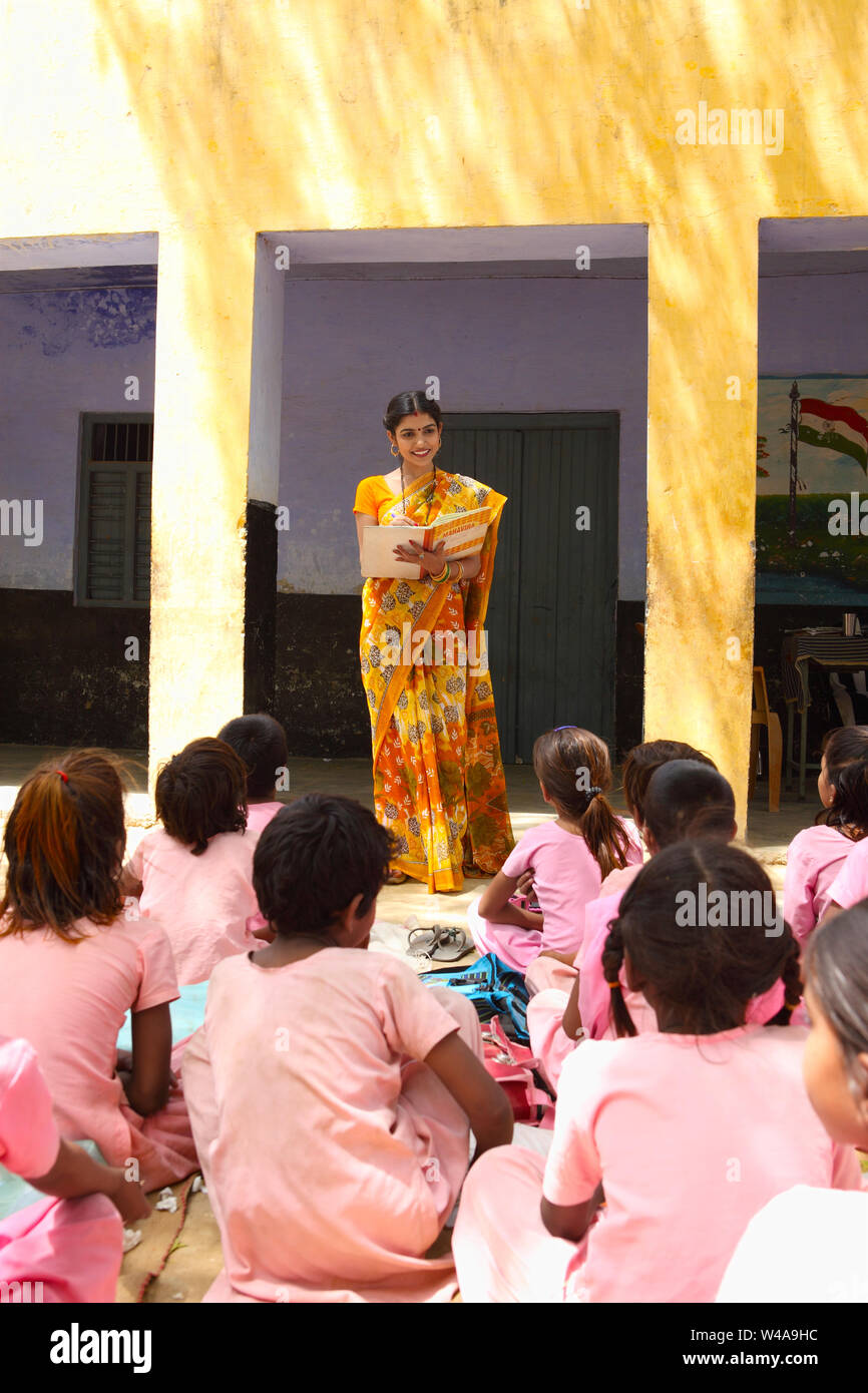 Female teacher teaching students in a class Stock Photo - Alamy