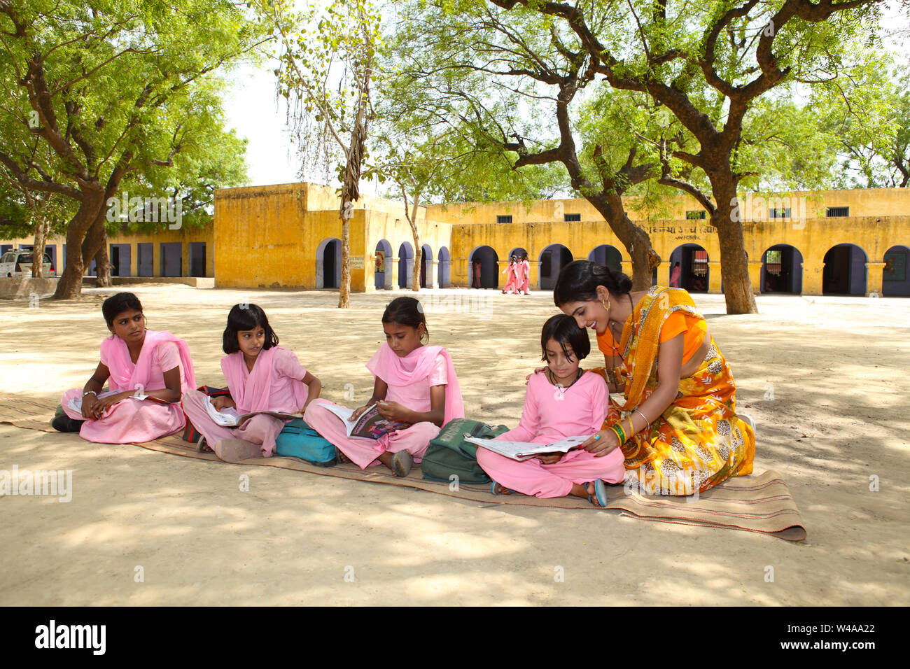 Female teacher teaching students in a class Stock Photo - Alamy