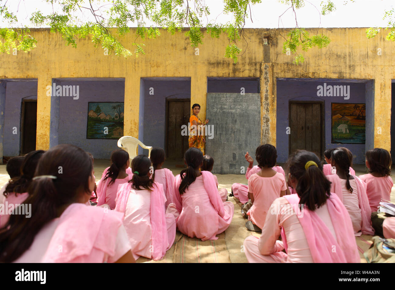 Female teacher teaching students in a class Stock Photo - Alamy