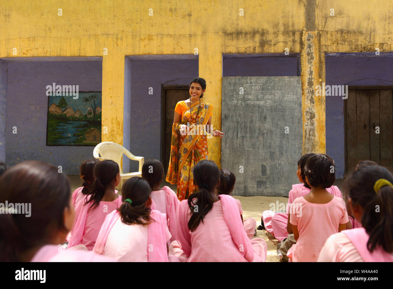 Female teacher teaching students in a class Stock Photo - Alamy