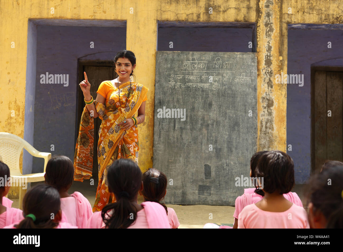 Female teacher teaching students in a class Stock Photo - Alamy