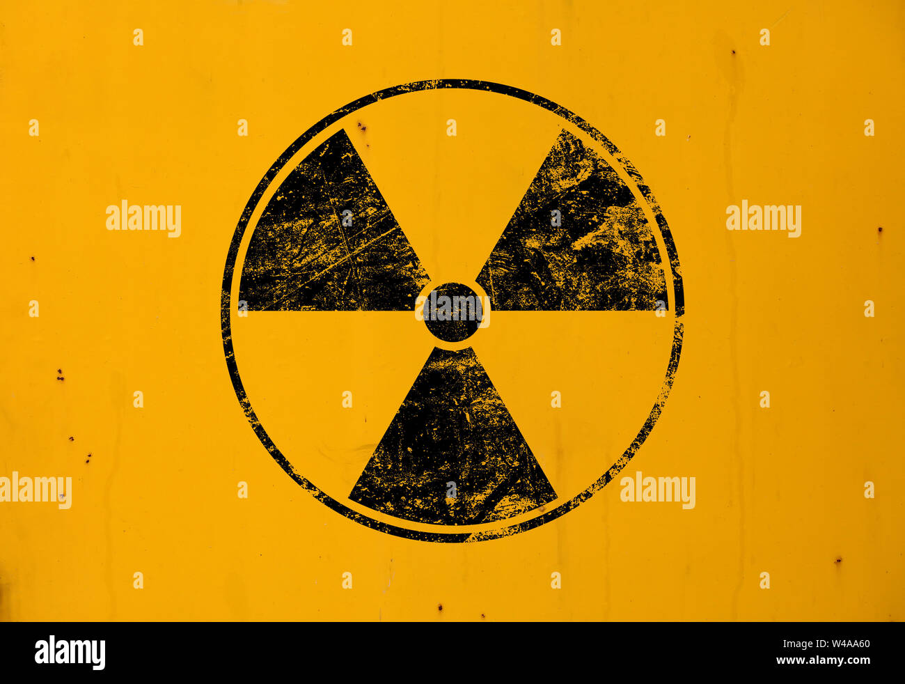 Black radioactive hazard warning sign painted over grunge yellow metal ...