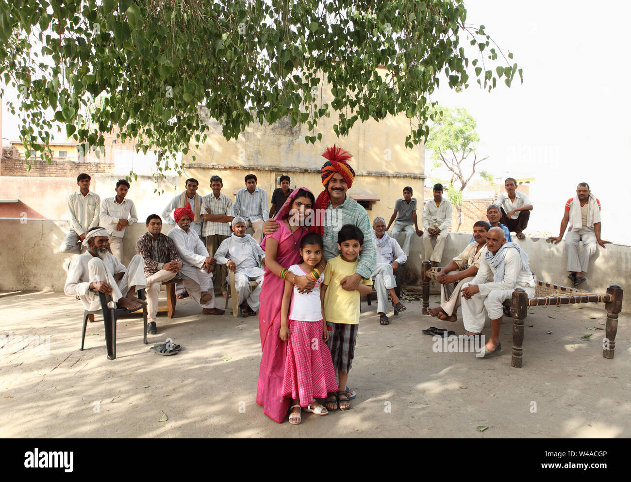 Rural family standing behind group of rural people sitting together ...