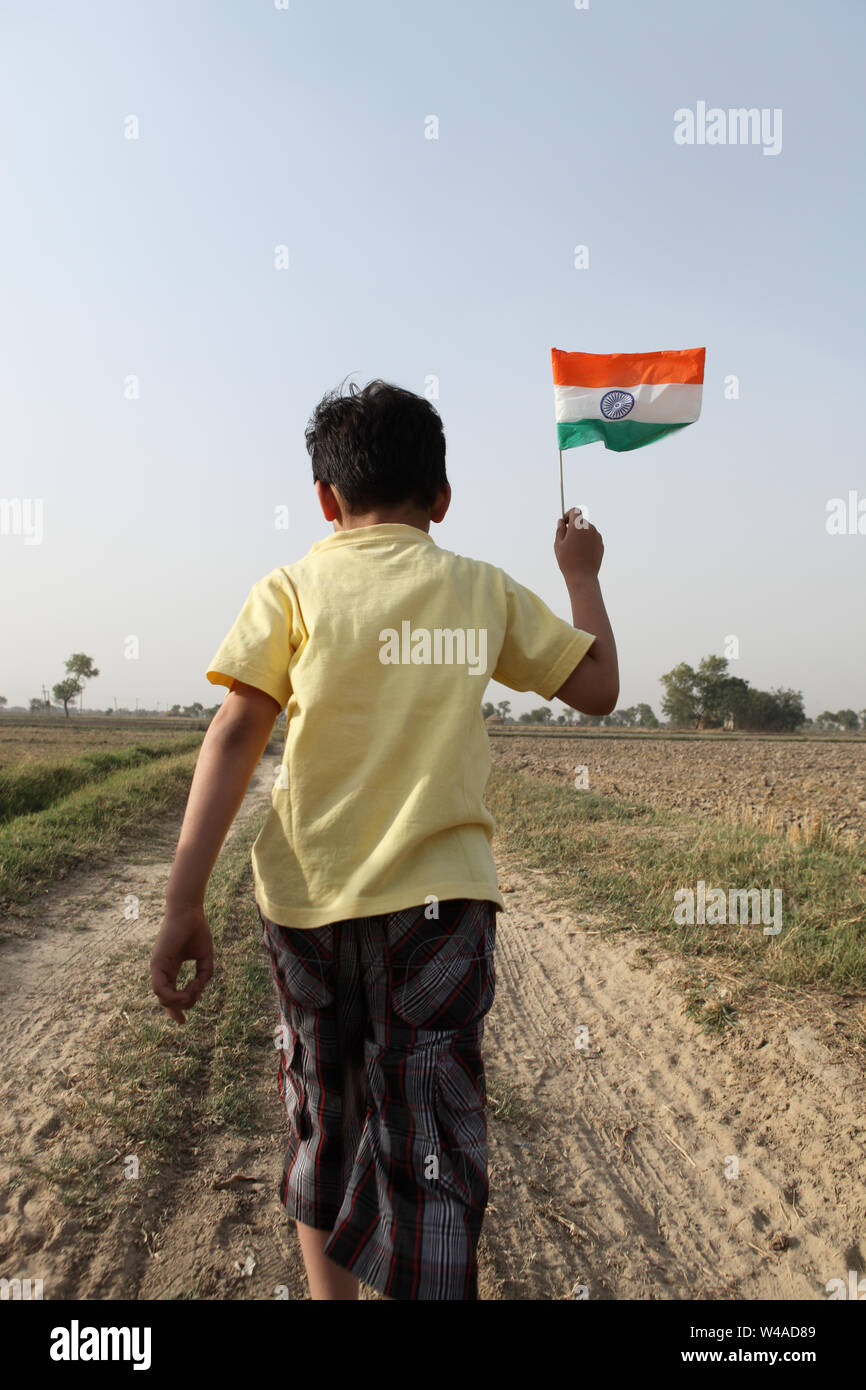 Rear view of a boy running with Indian flag in a field Stock Photo - Alamy